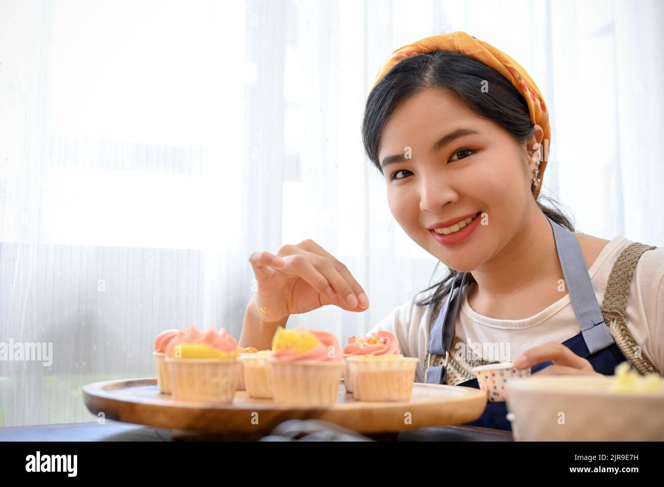 Beautiful young Asian female baker decorating her beautiful homemade ...