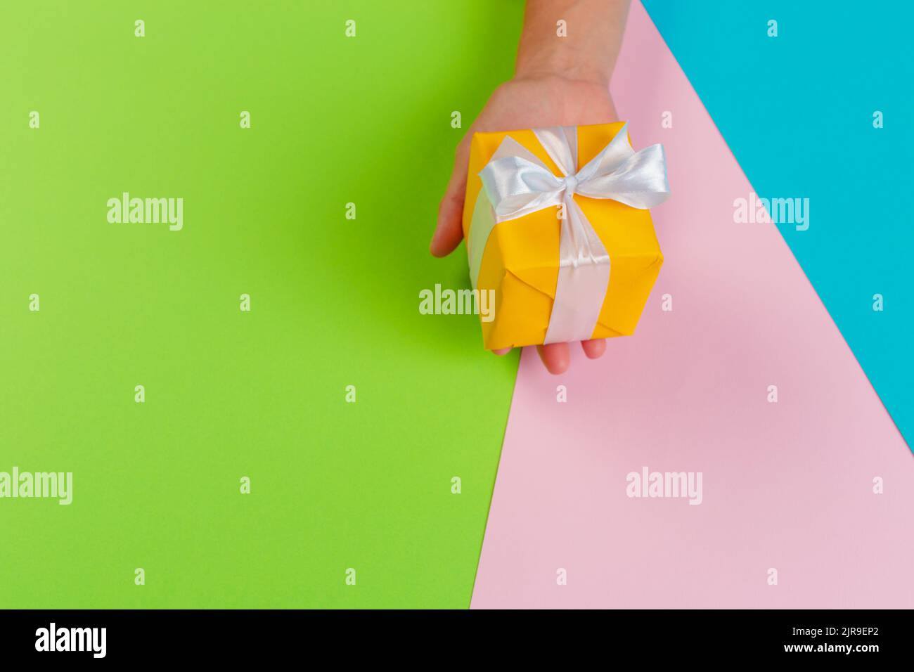 Woman holding gift box on color background Stock Photo - Alamy