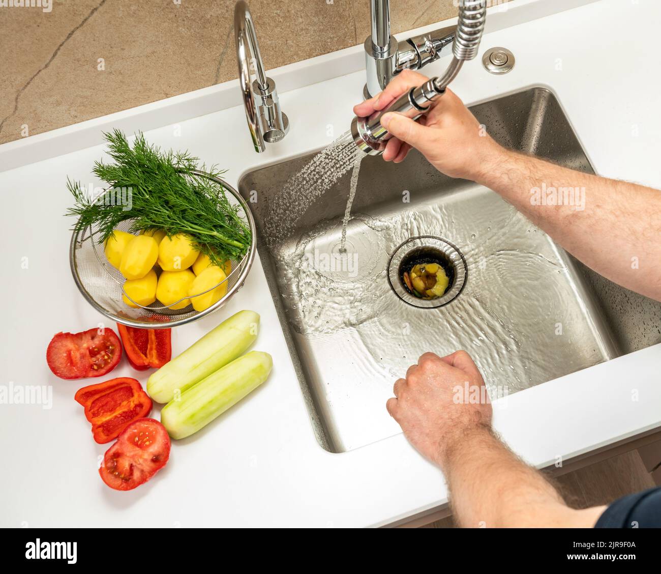 A man washes food waste into a dispenser Stock Photo - Alamy