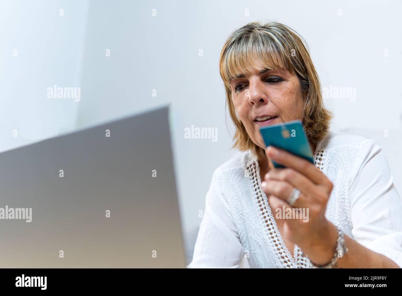 Mature woman with a credit card in her hand shopping online with her ...