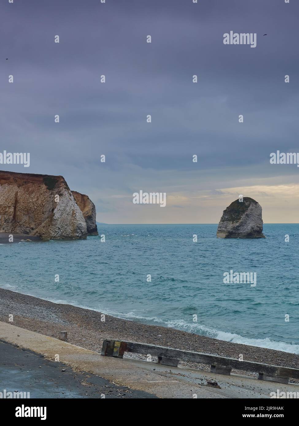 An isolated rock outcrop surrounded by sea and looking back to cliffs ...