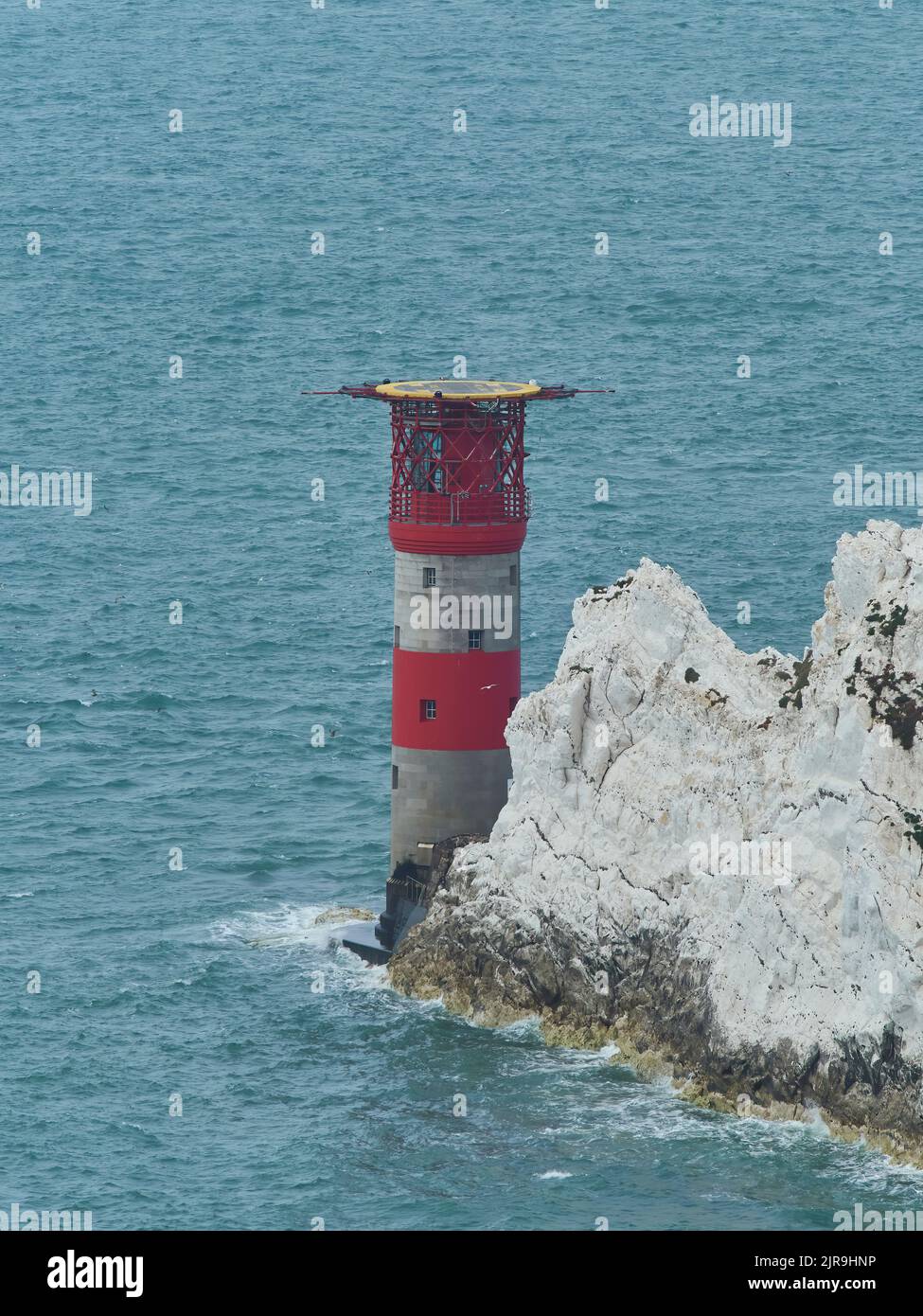 The lighthouse at The Needles in a steely sea and behind jagged, tooth ...