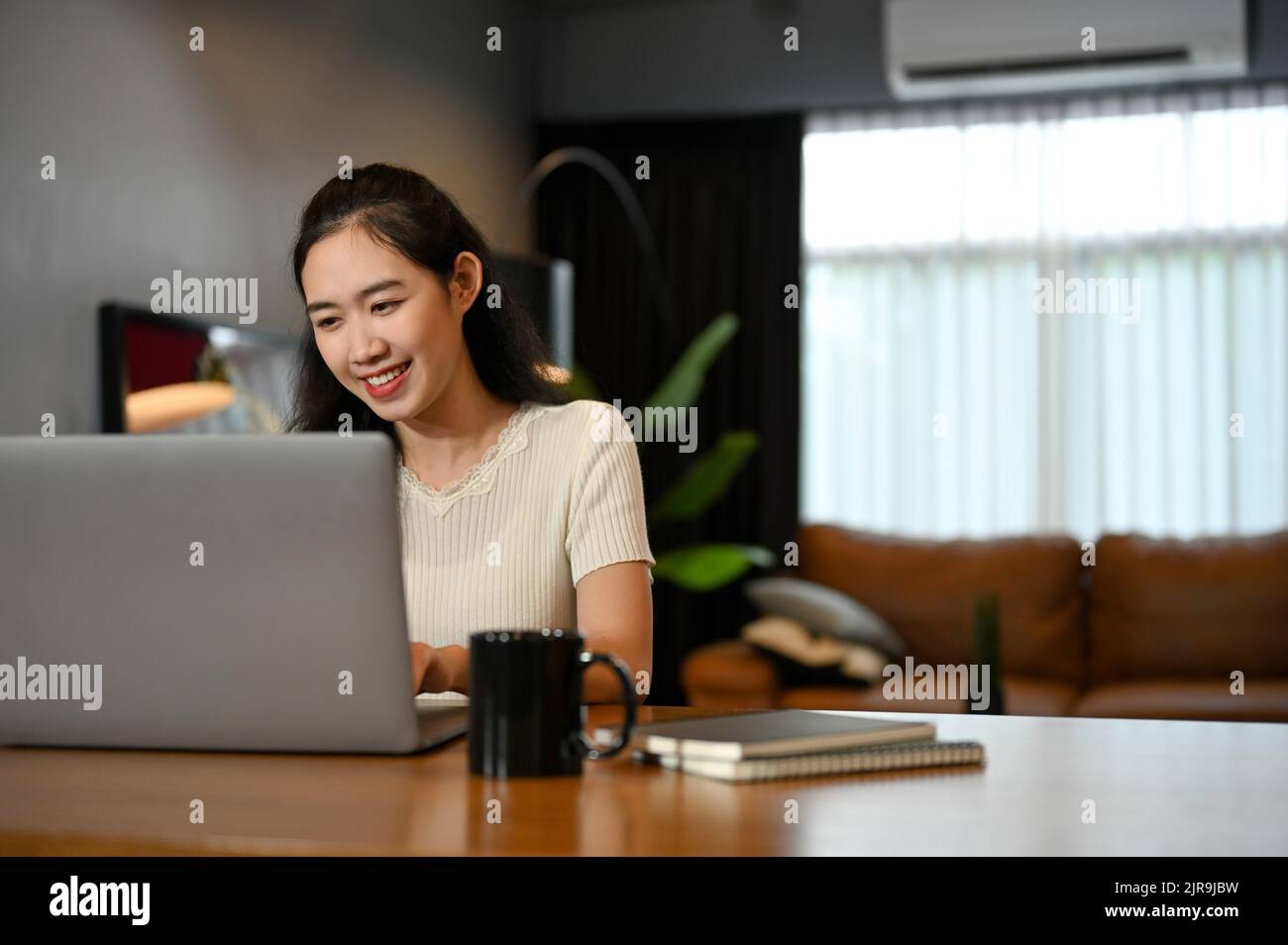 Happy young Asian female college student using portable laptop computer ...