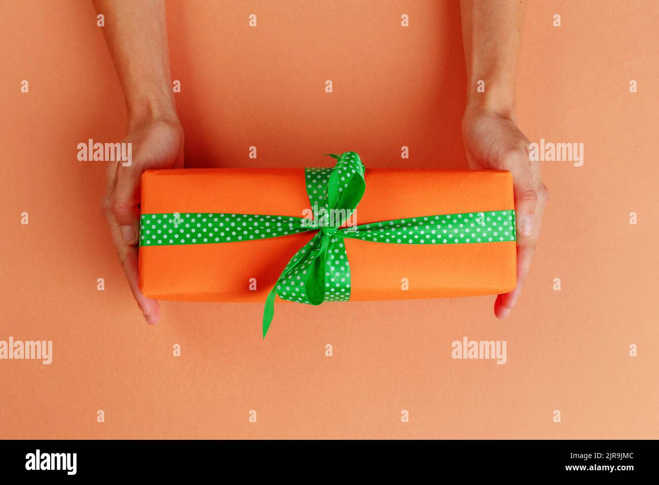 Woman holding gift box on color background Stock Photo - Alamy