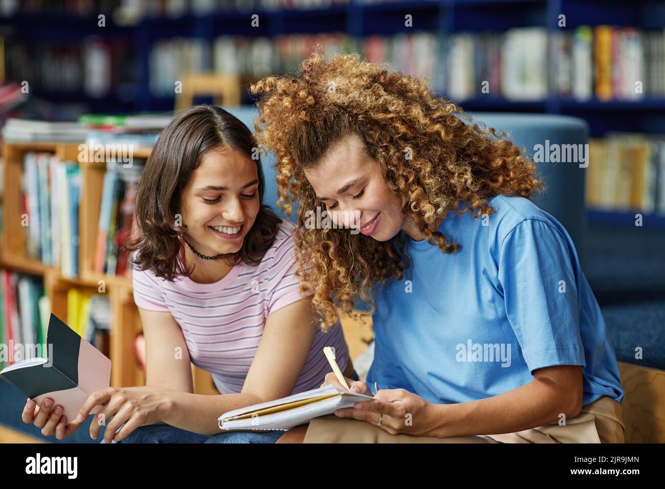 Vibrant portrait of two young girls studying in college library and ...