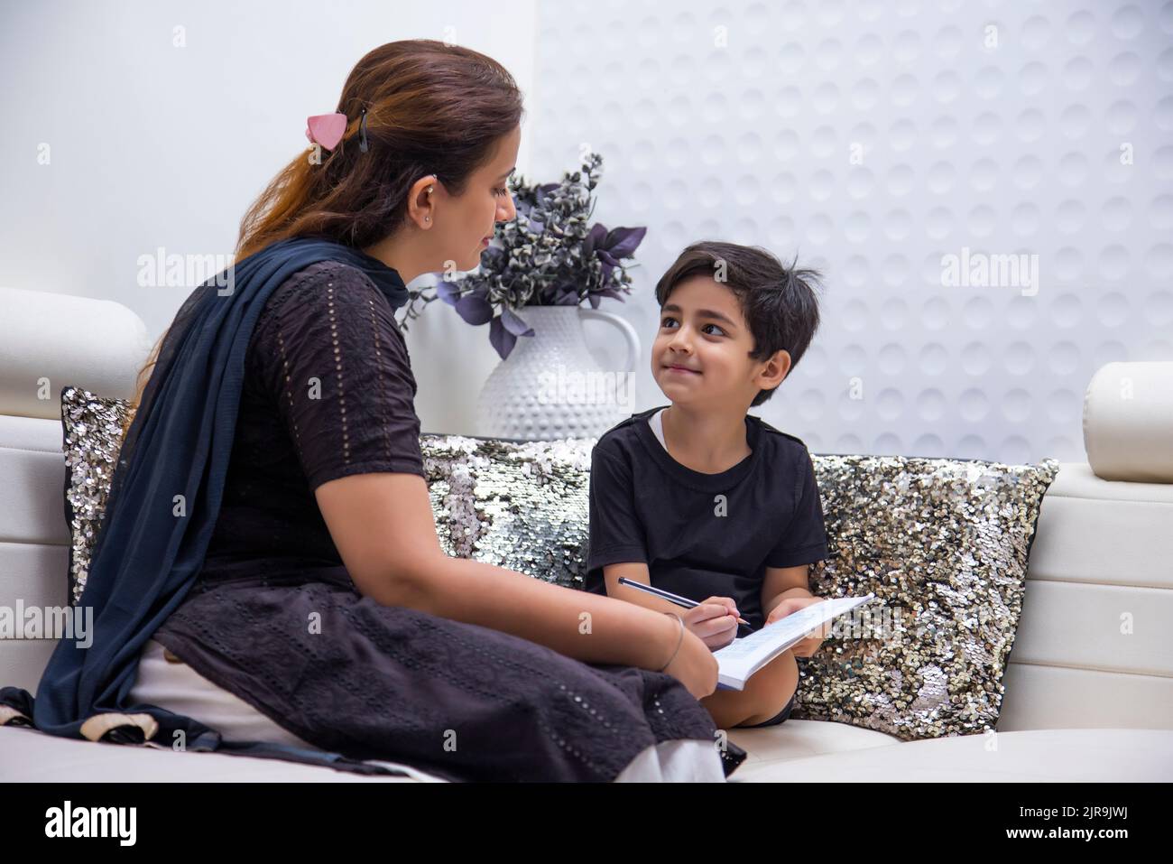Mother helping her son with homework on sofa at home Stock Photo - Alamy