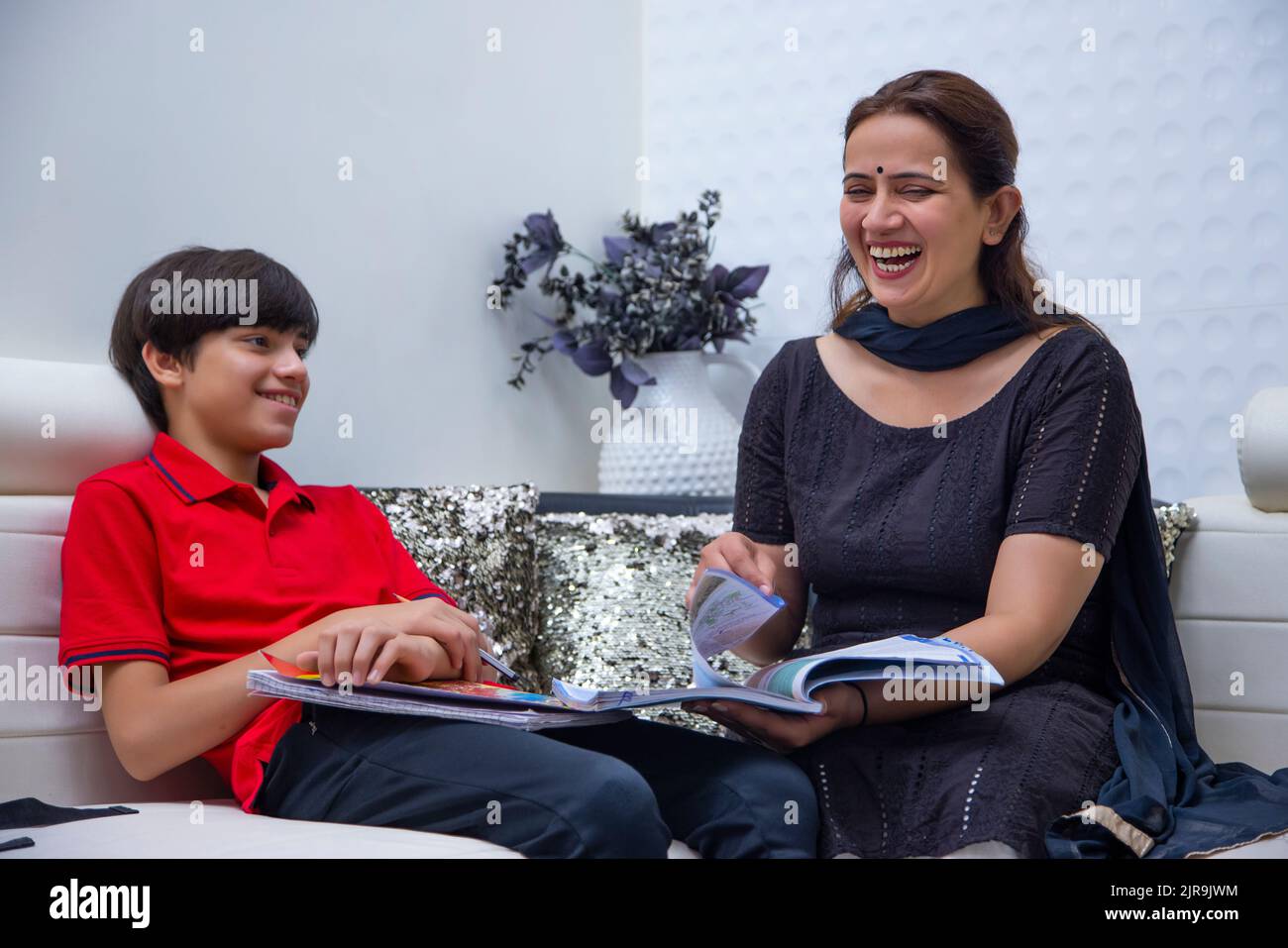Mother helping her son with homework on sofa at home Stock Photo - Alamy