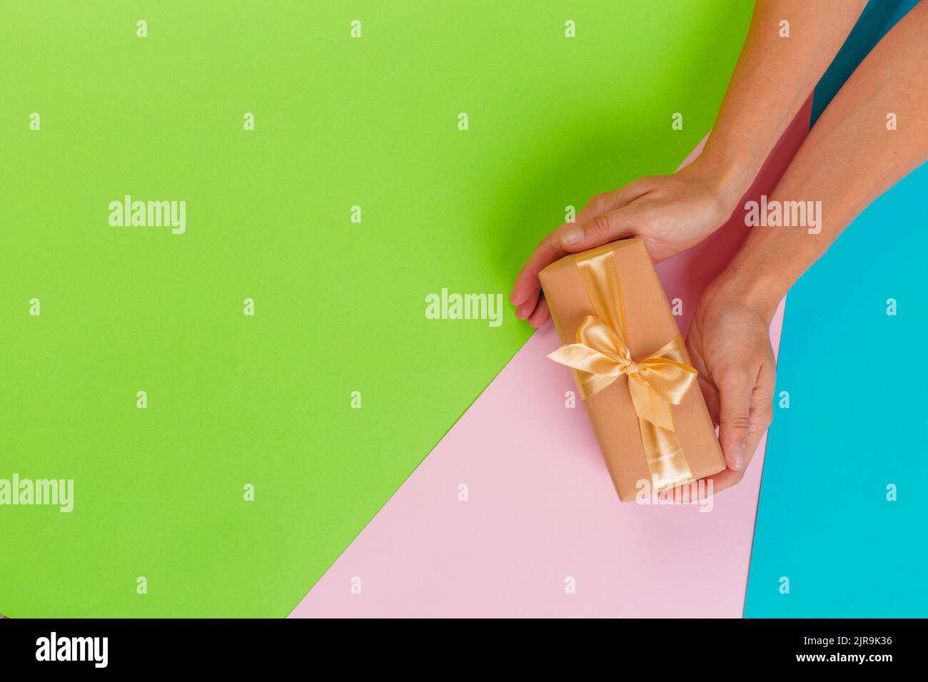 Woman holding gift box on color background Stock Photo - Alamy