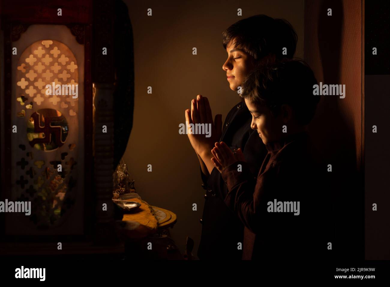 Portrait of two brothers praying together to God with folded hands ...
