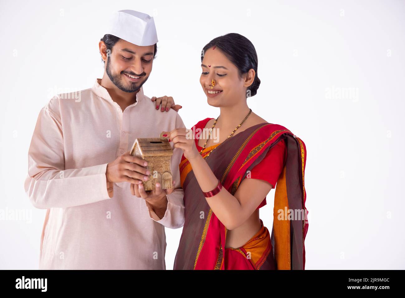 Maharashtrian couple putting coin into money box Stock Photo - Alamy