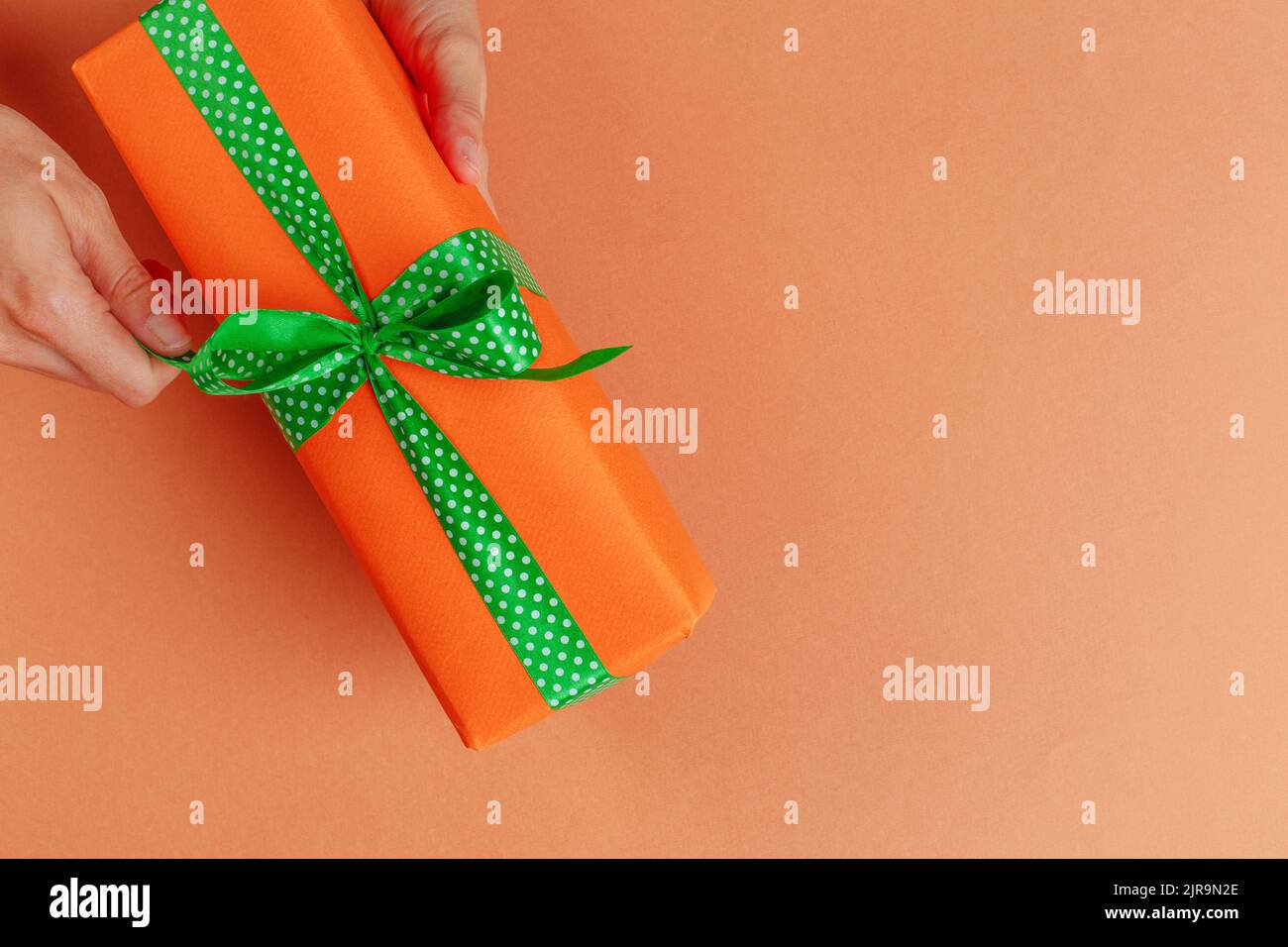 Woman holding gift box on color background Stock Photo - Alamy