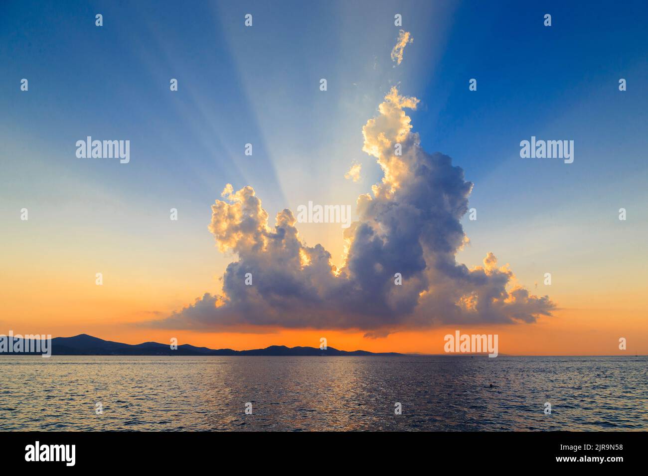 The rays of the sun setting at sunset behind a cloud of sun unusually ...