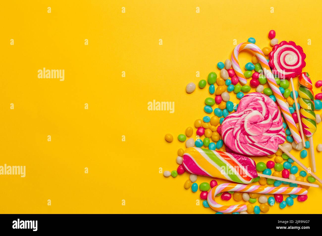 colored candies on yellow background Stock Photo - Alamy