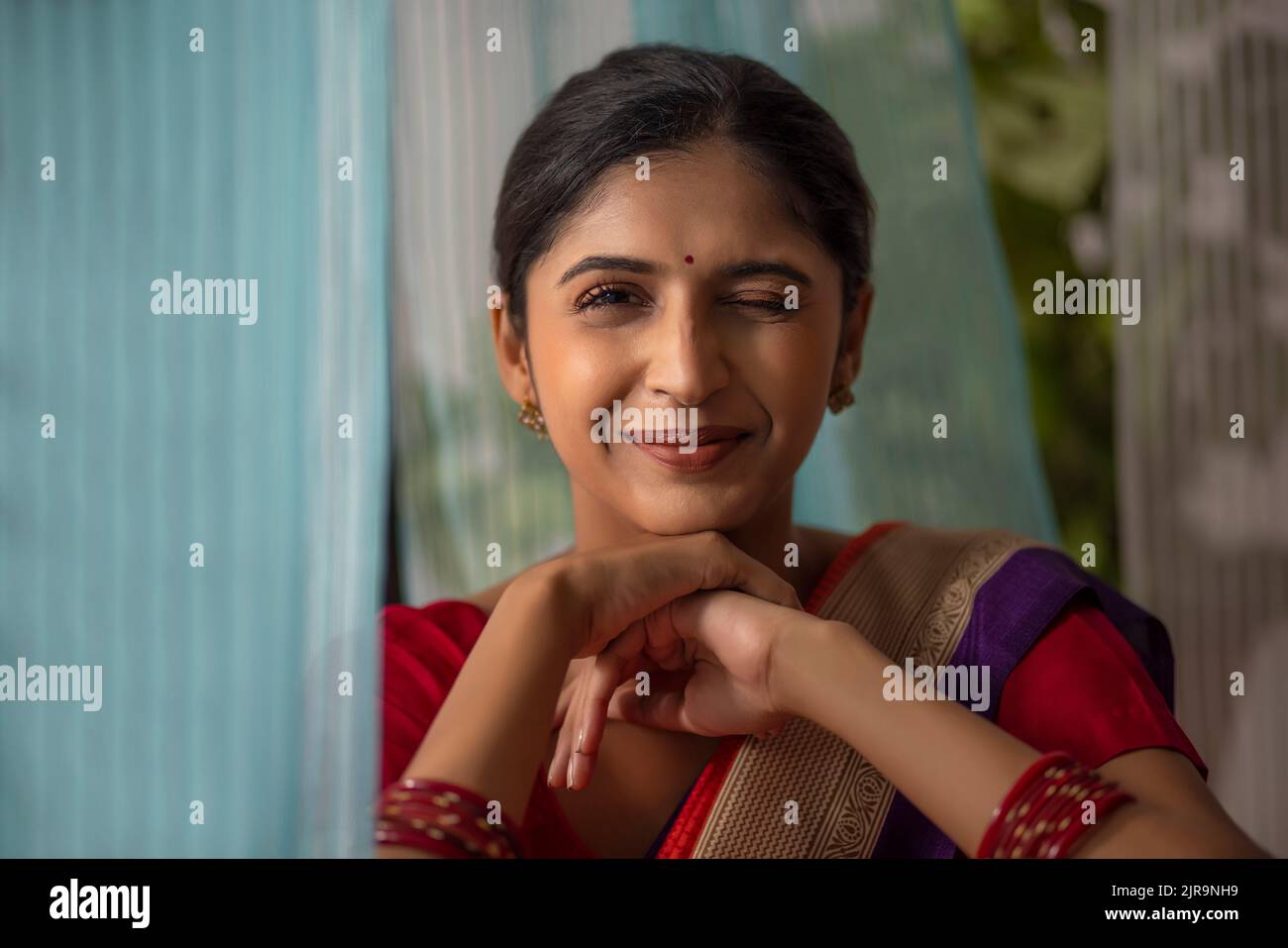 Close-up portrait of smiling woman gesturing with one eye closed Stock ...