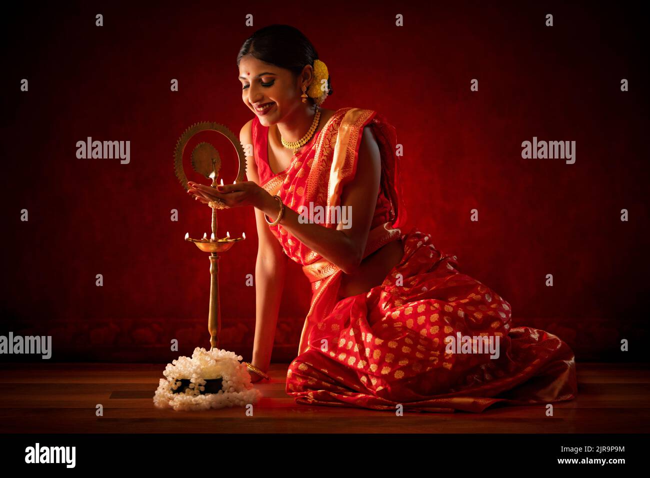 Woman in traditional outfit lighting oil lamp on the occasion of Diwali ...