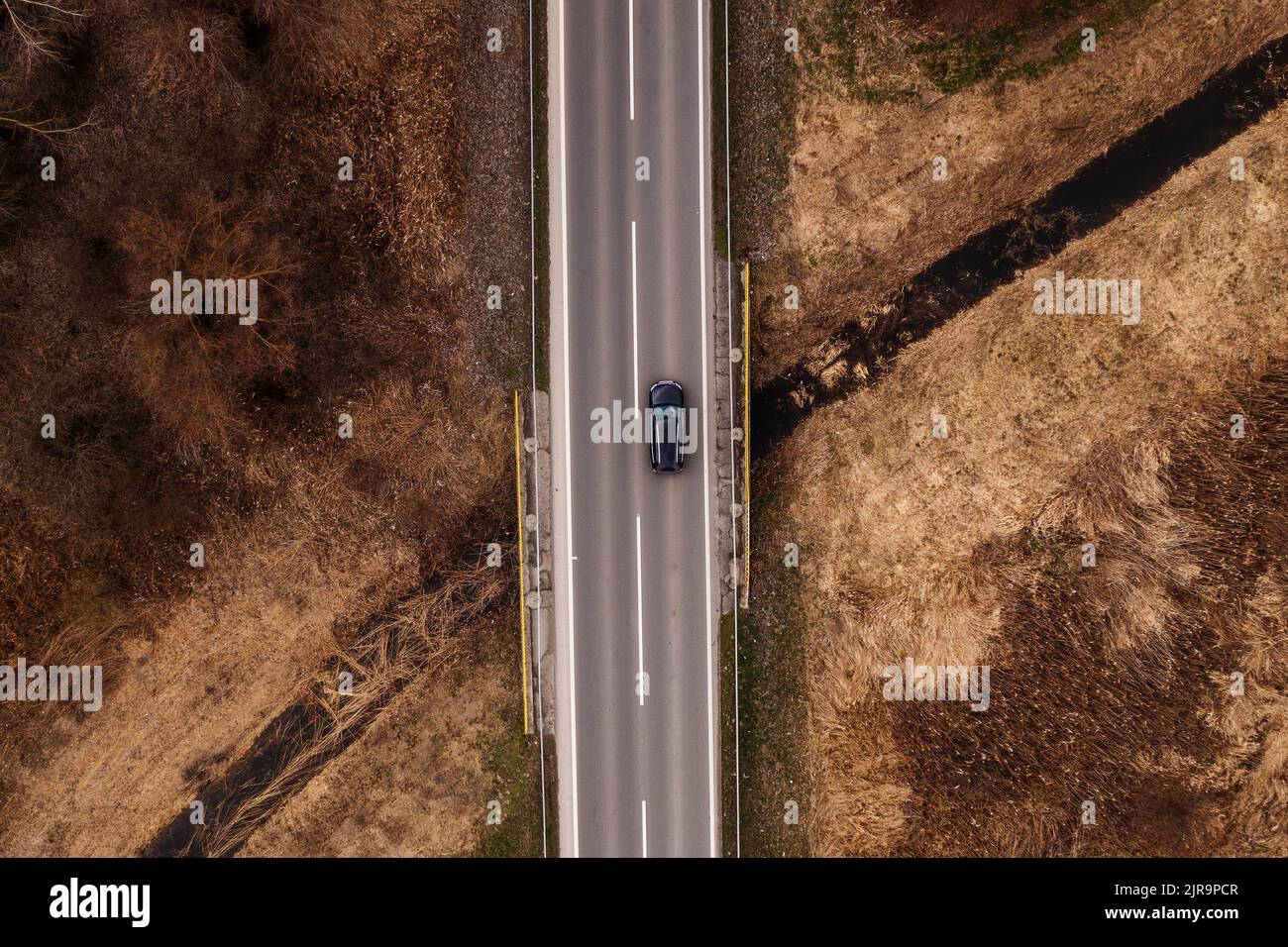 Aerial view of black car on the highway bridge over small creek, top ...