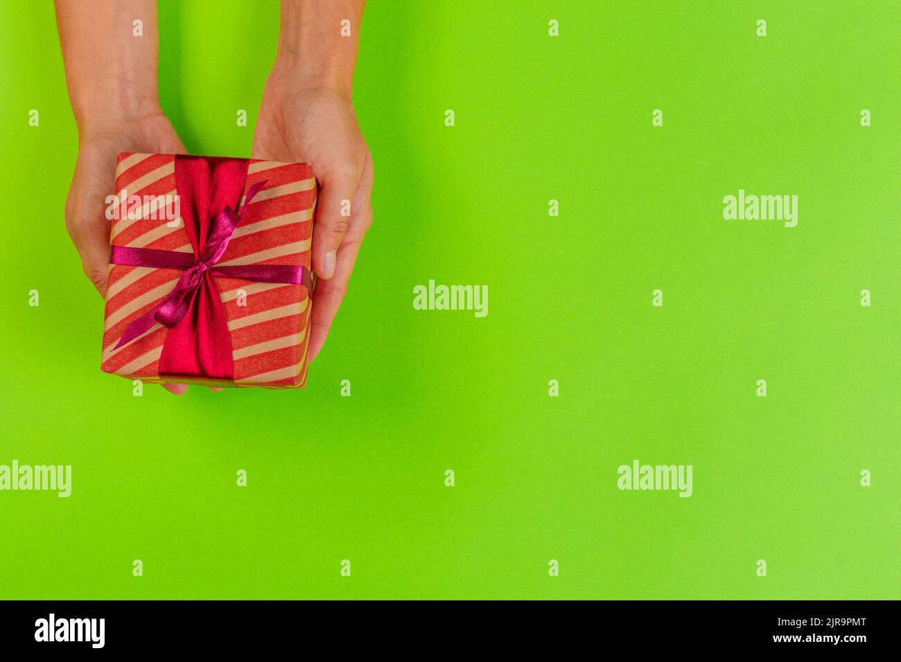 Woman holding gift box on color background Stock Photo - Alamy