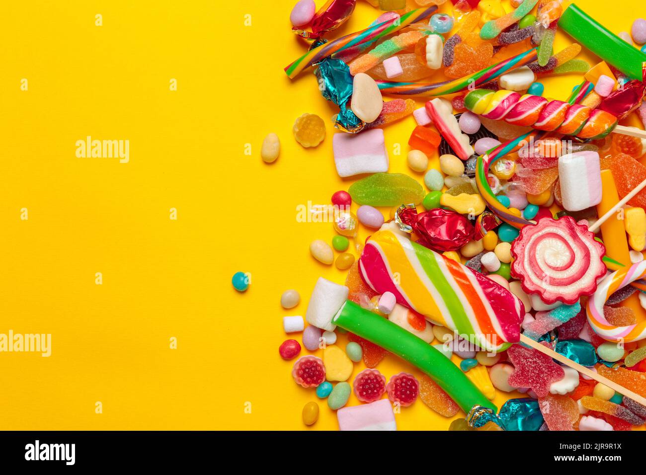 colored candies on yellow background Stock Photo - Alamy