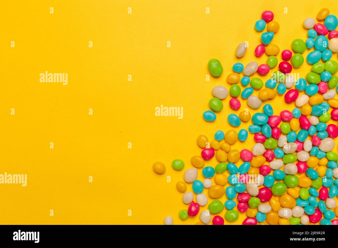 colored candies on yellow background Stock Photo - Alamy
