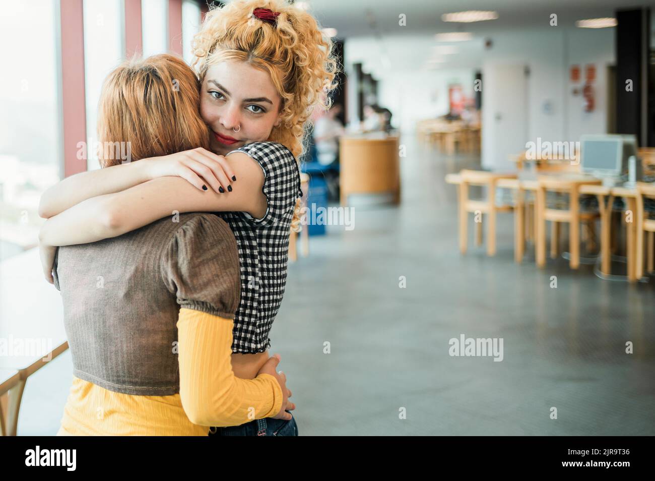 Young girlfriends hugging in library Stock Photo - Alamy