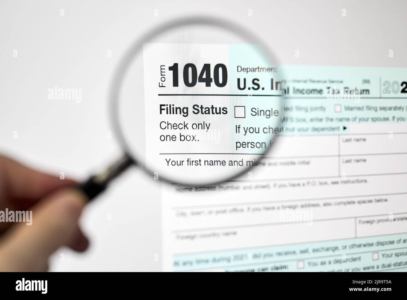 Man looking through a magnifying glass at U.S. Individual Income Tax ...