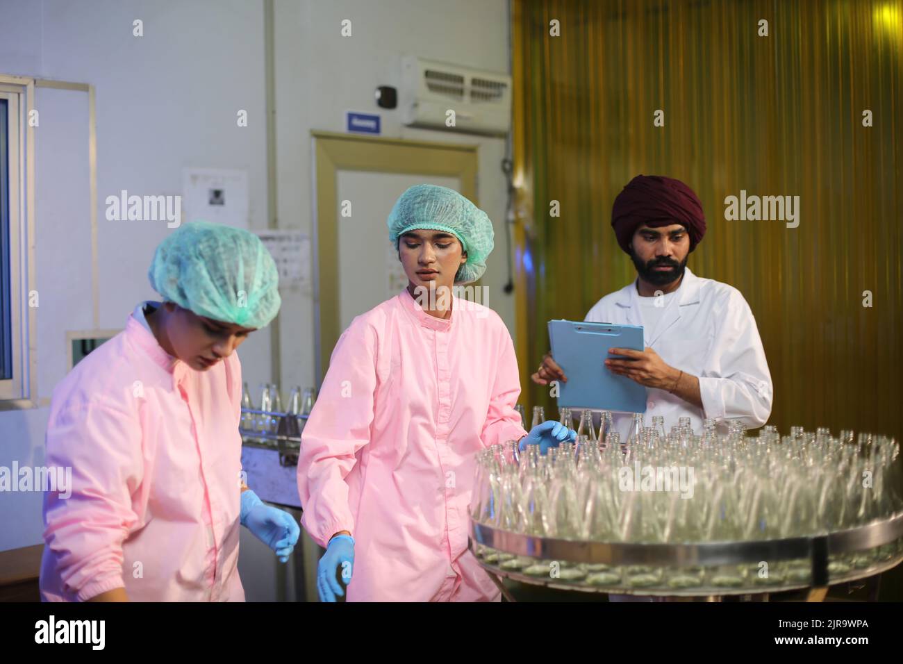 worker controlling the work of machine in production line at beverage ...