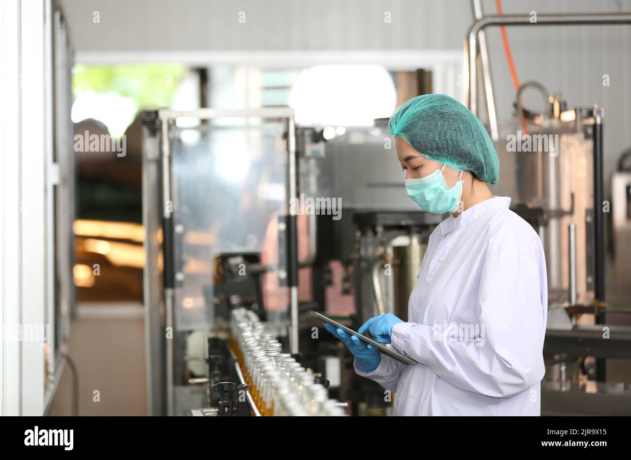 worker controlling the work of machine in production line at beverage ...