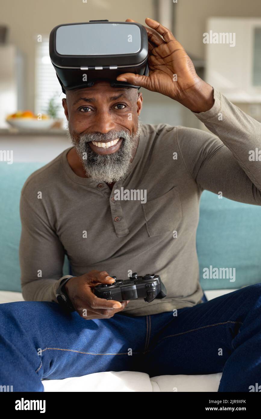 Portrait of senior african american man playing video games and using ...