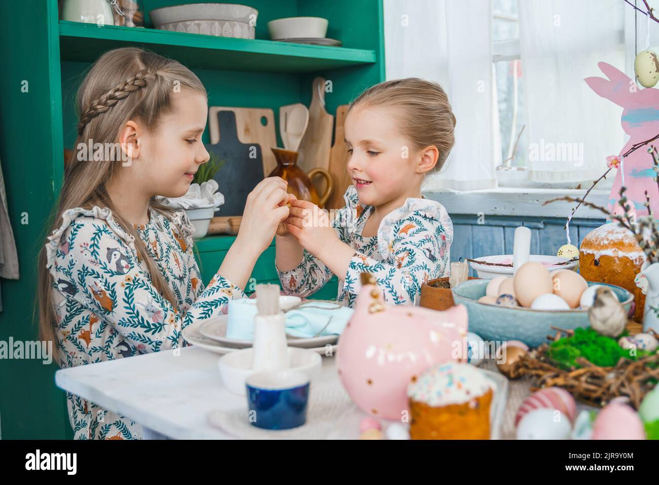 Girls, sisters at table with Easter decoration. Celebration in kitchen ...