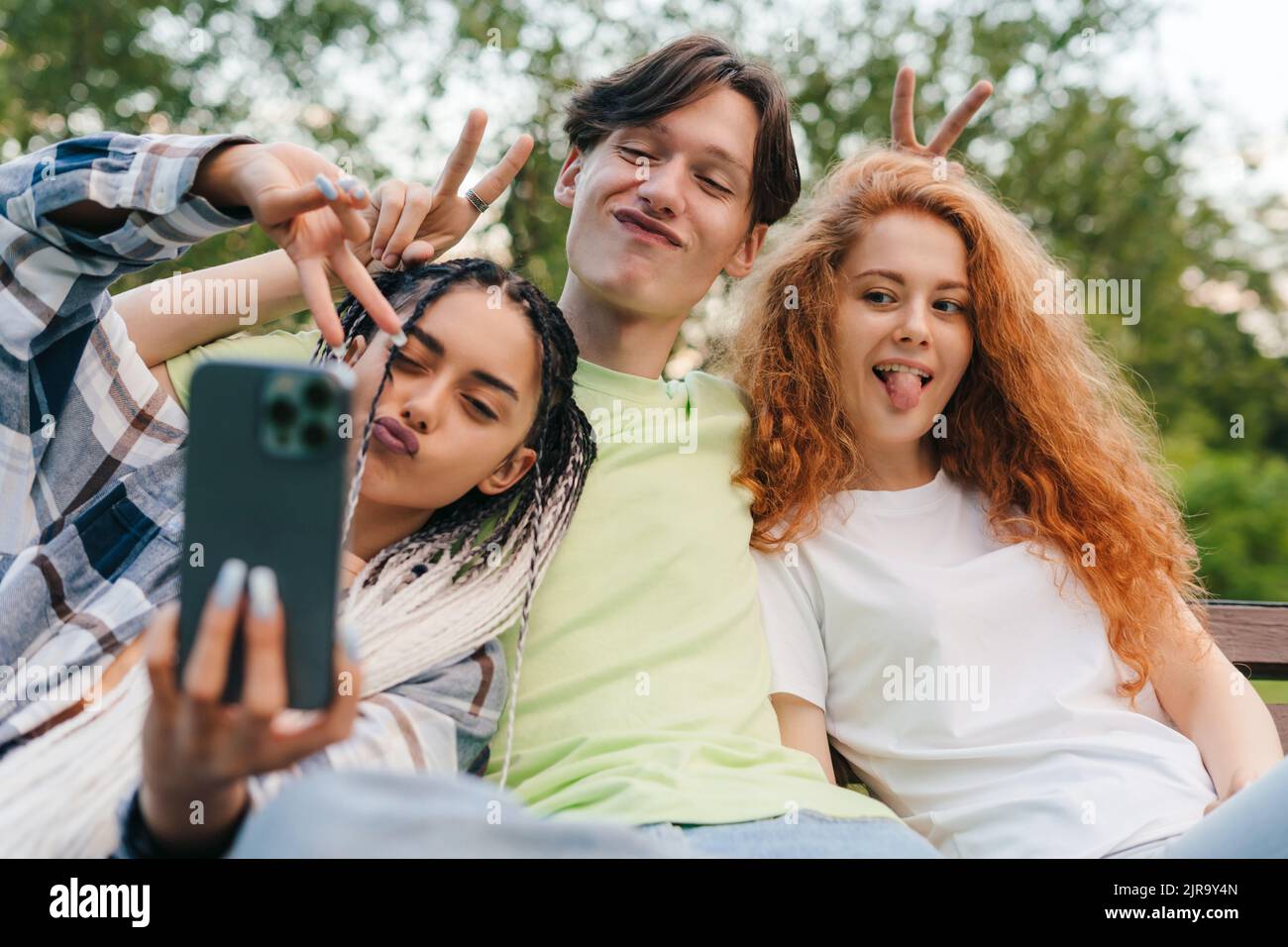 Three teenagers taking a selfie showing v sign with their fingers on a ...