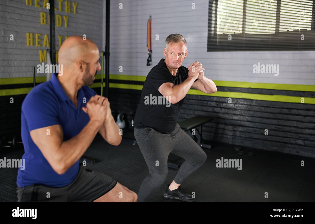 Male personal trainer motivating and assisting elderly senior man while ...