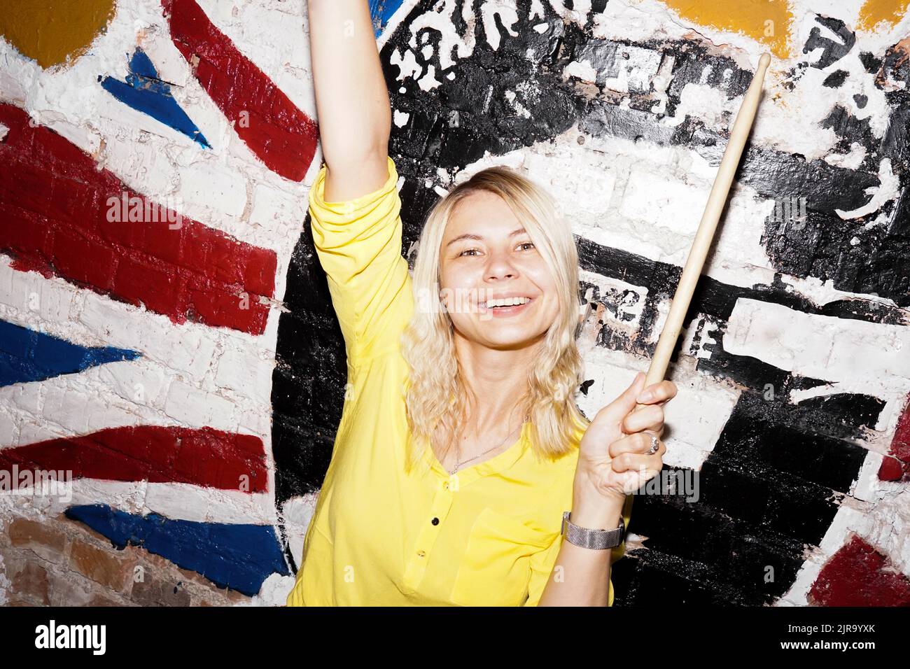 A young cheerful blonde plays a drum set for a computer game. Party ...