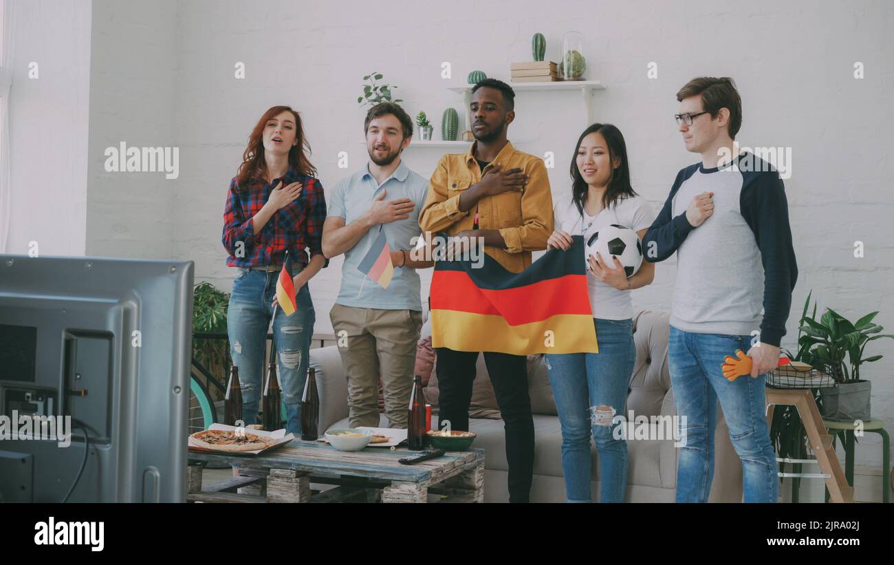 Multi-ethnic group of friends sport fans listening and singing German ...