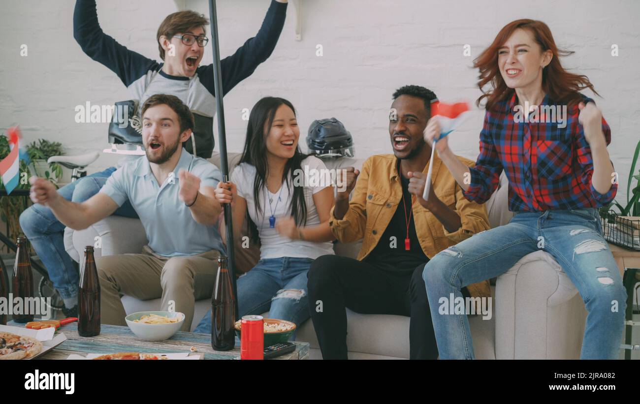 Diverse group of friends sport fans with Dutch national flags watching ...