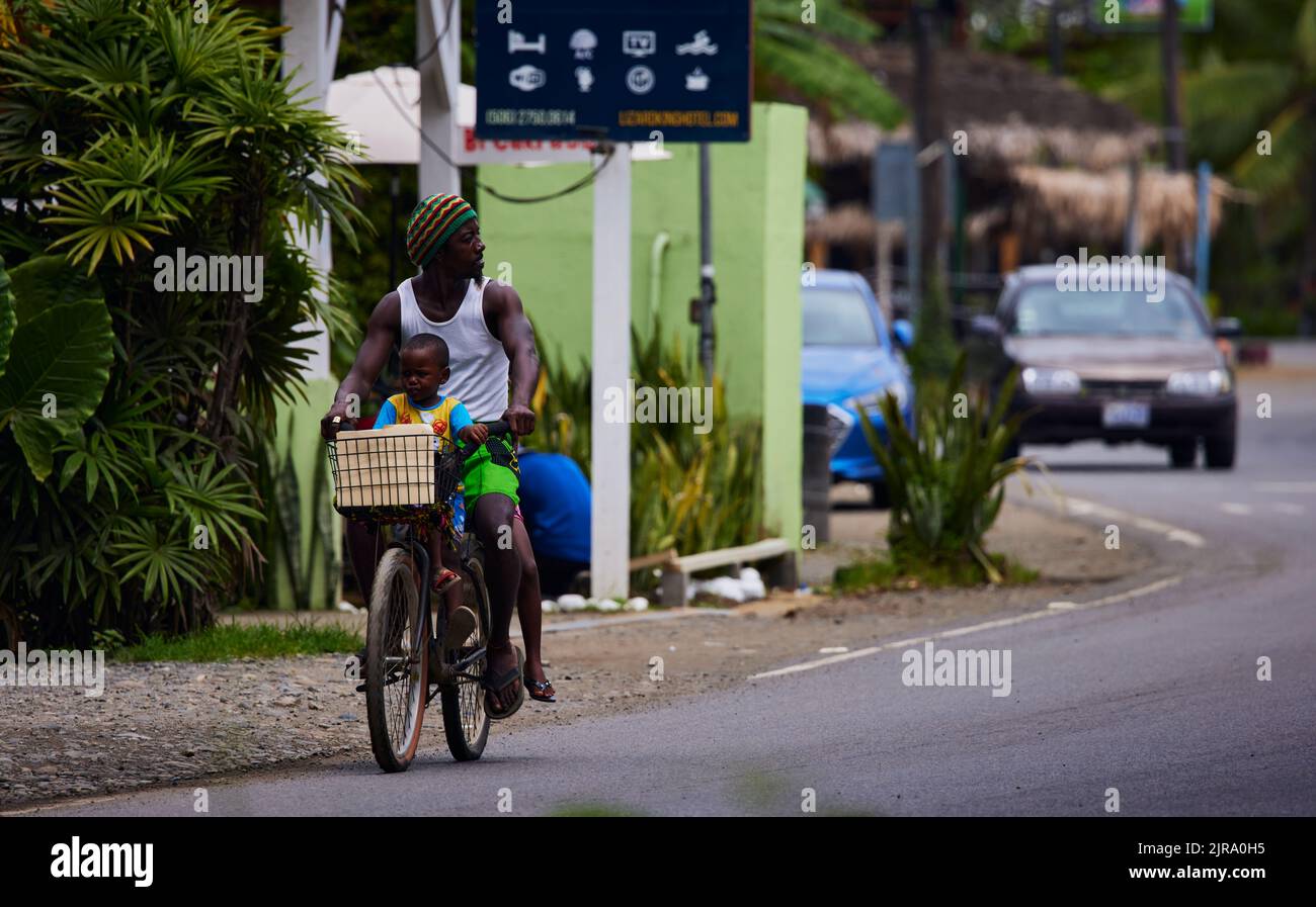 A local man riding a bicycle with his child on a road in the daylight ...