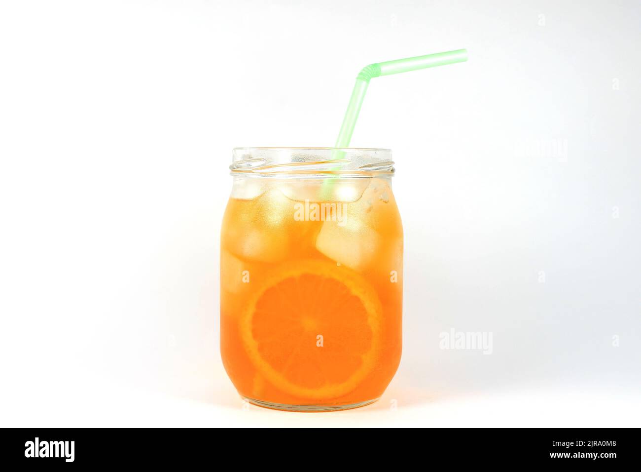 A glass cup of an orange Aperol spritz with green straw in it on a ...
