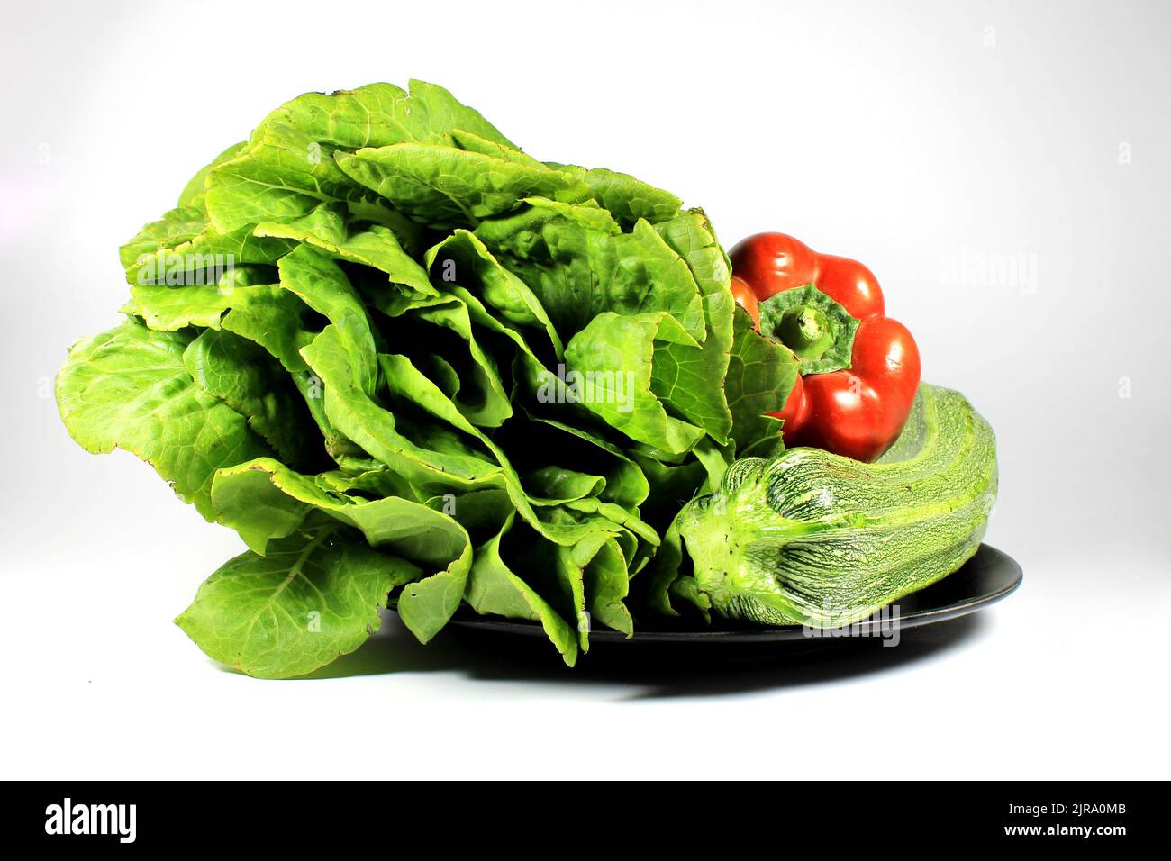 A closeup of a black plate with vegetables on a white background Stock ...