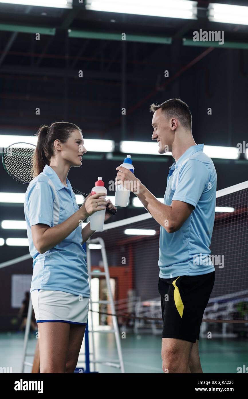 Smiling boyfriend and girlfriend talking and drinking water after game ...