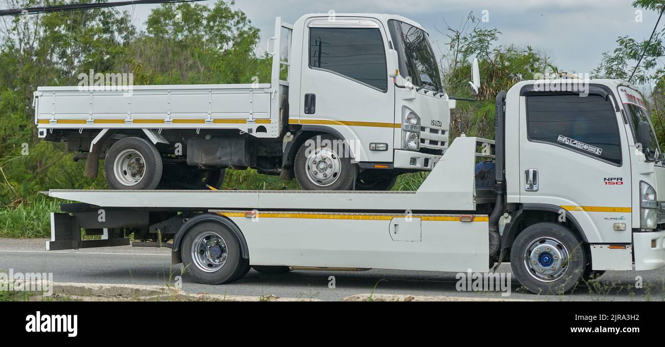 A small white truck being transported on a larger but similar looking ...
