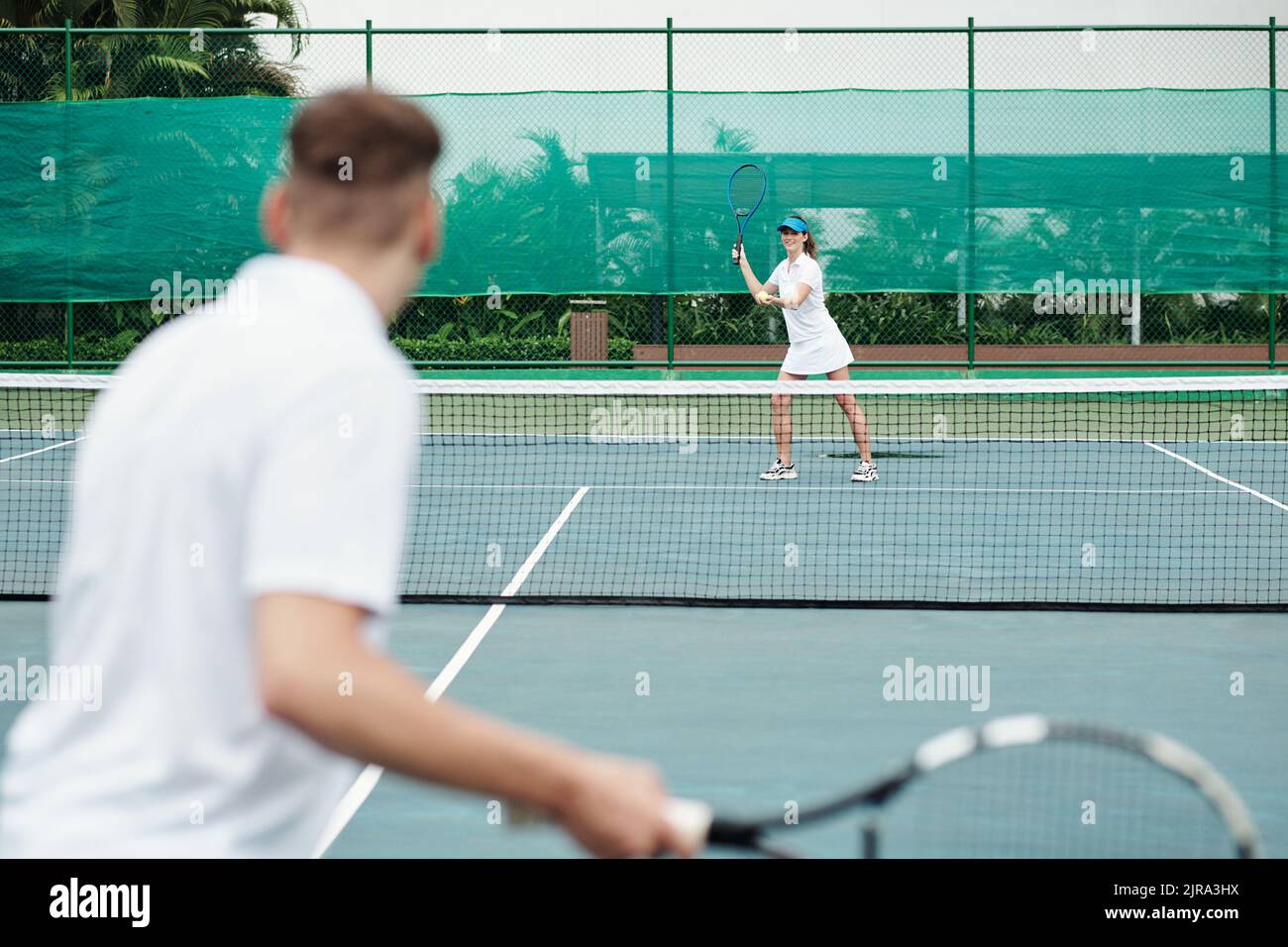 Smiling young woman serving ball when playing tennis with friend Stock ...