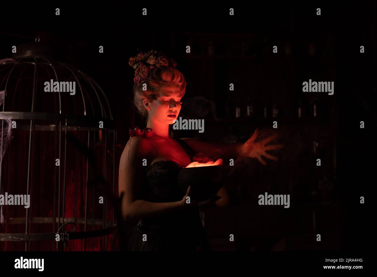 Halloween witch with cauldron. Beautiful young woman conjuring, making ...
