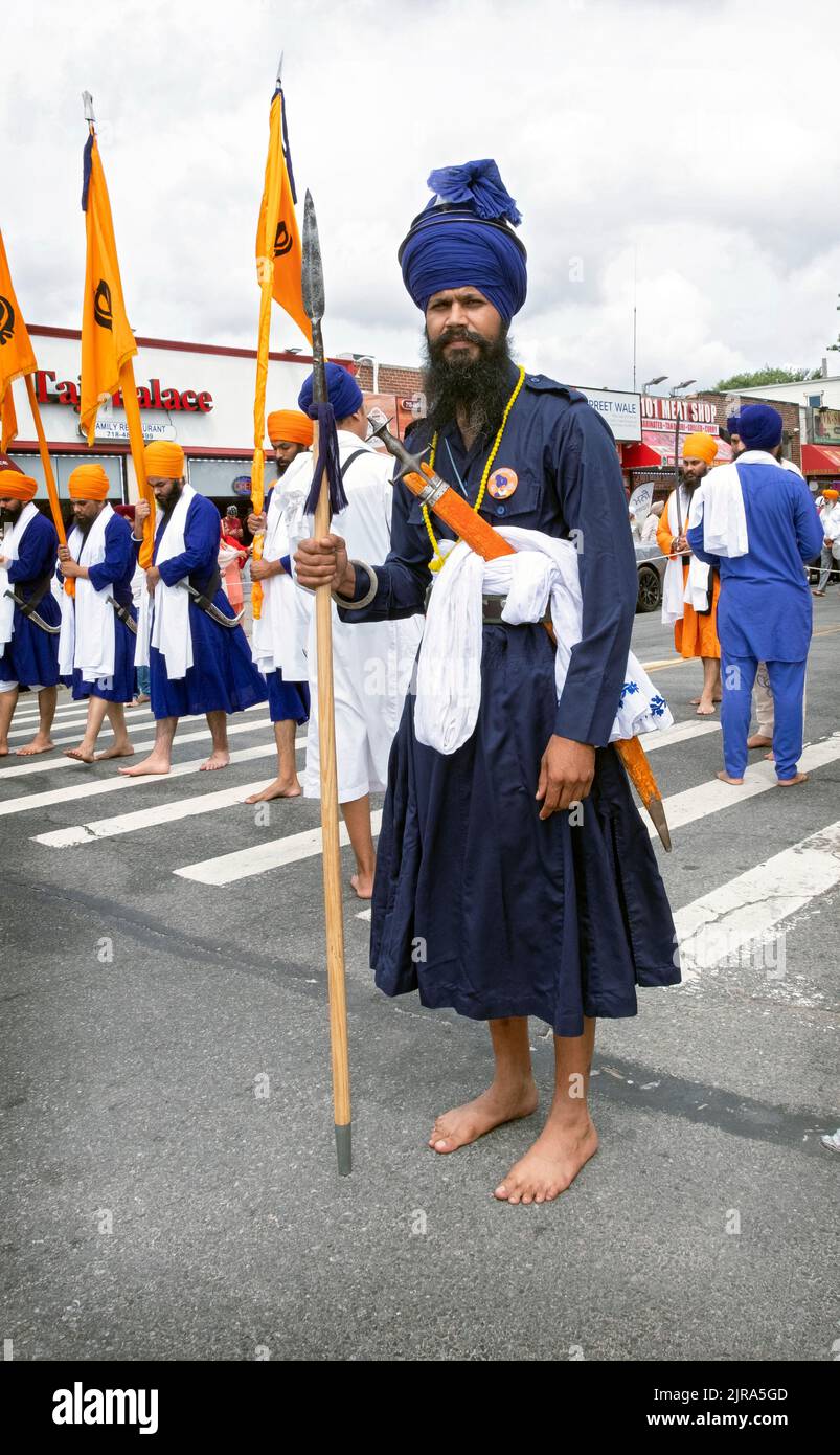Posed portrait of a Sikh devotee in blue clothing with a spear and a ...