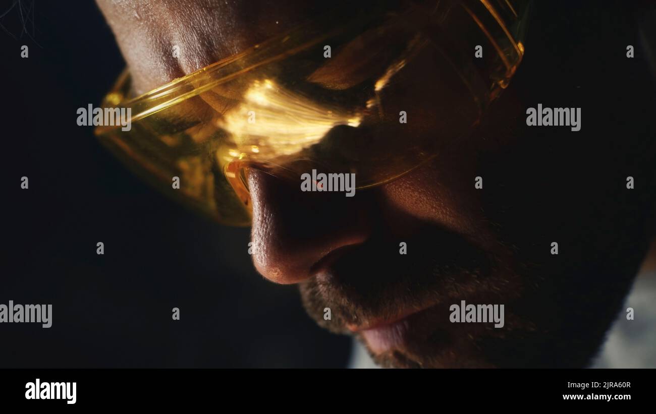 Close shot of serious male worker in protective goggles metalworking in ...
