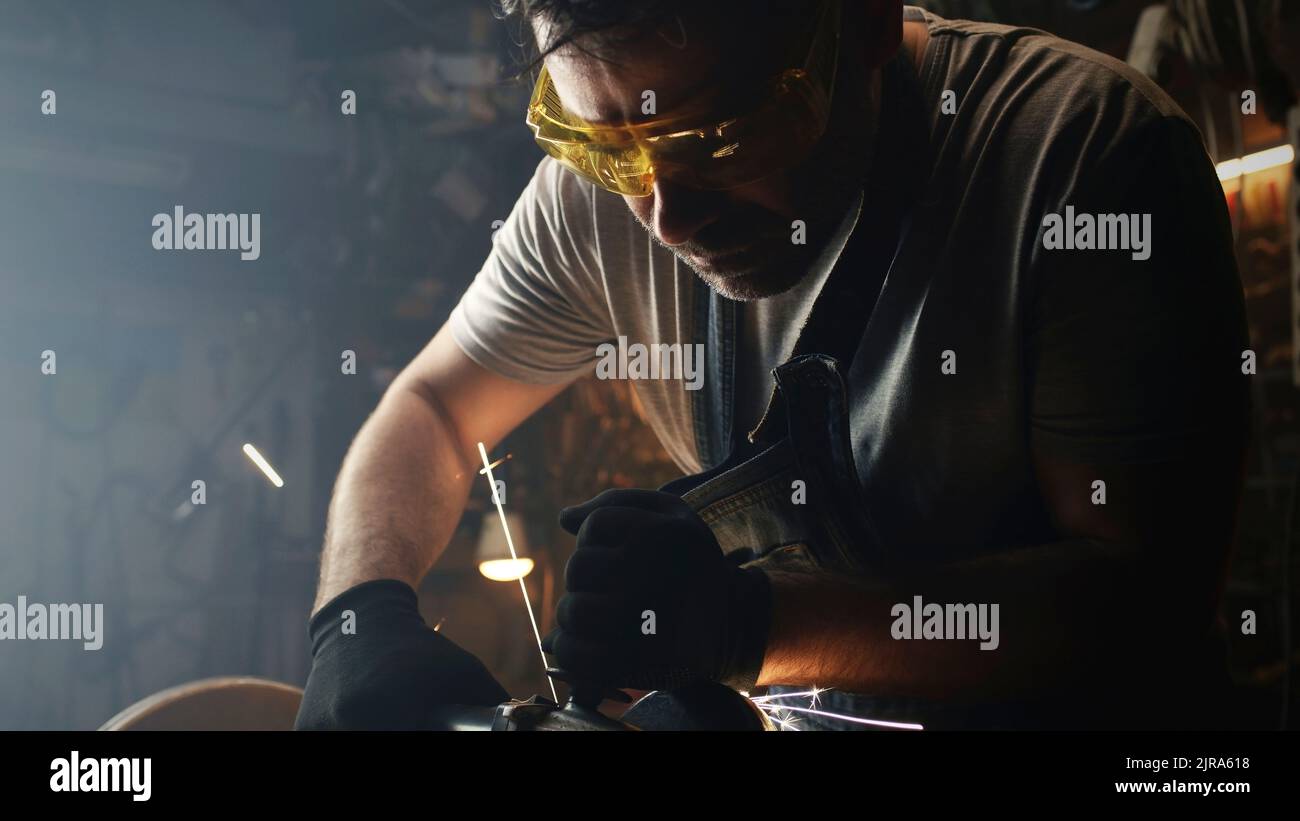 Man in uniform and protective goggles turning on a circular saw and ...