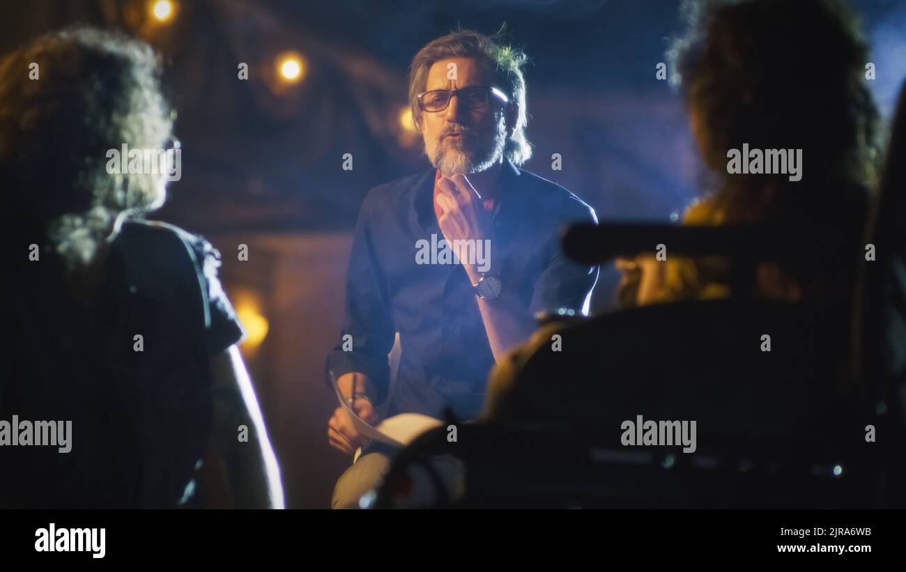 Director at the rehearsal sitting on the dim stage illuminated by a ...