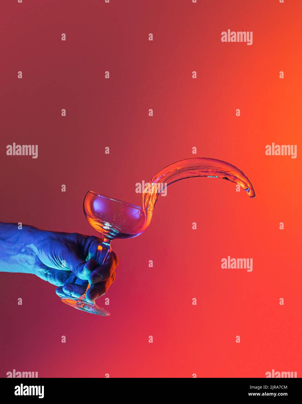 Flying water. Male hand pouring clean fluid from cocktail glass over ...