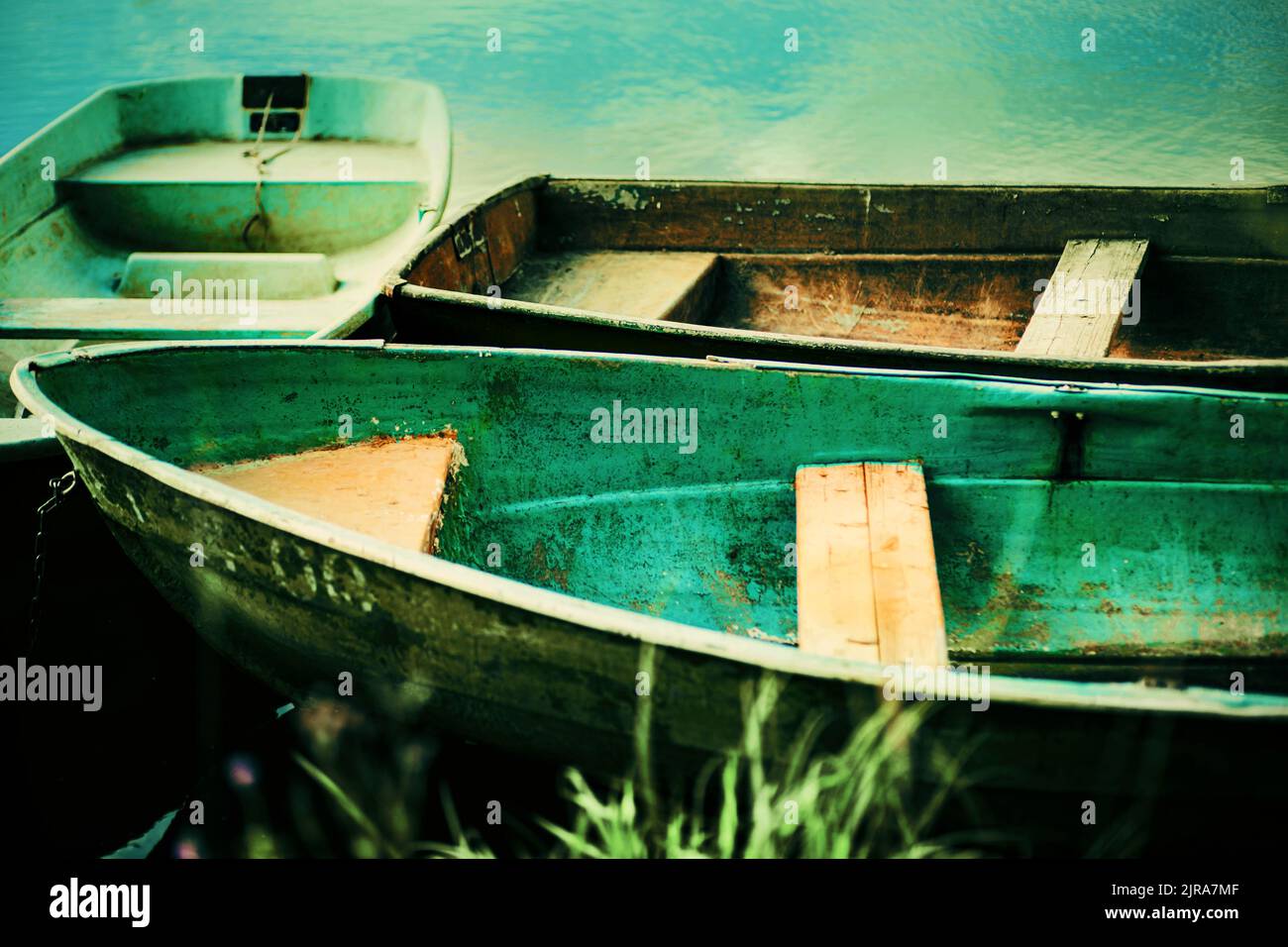 Old empty blue fishing boats float near the grassy shore on the blue ...