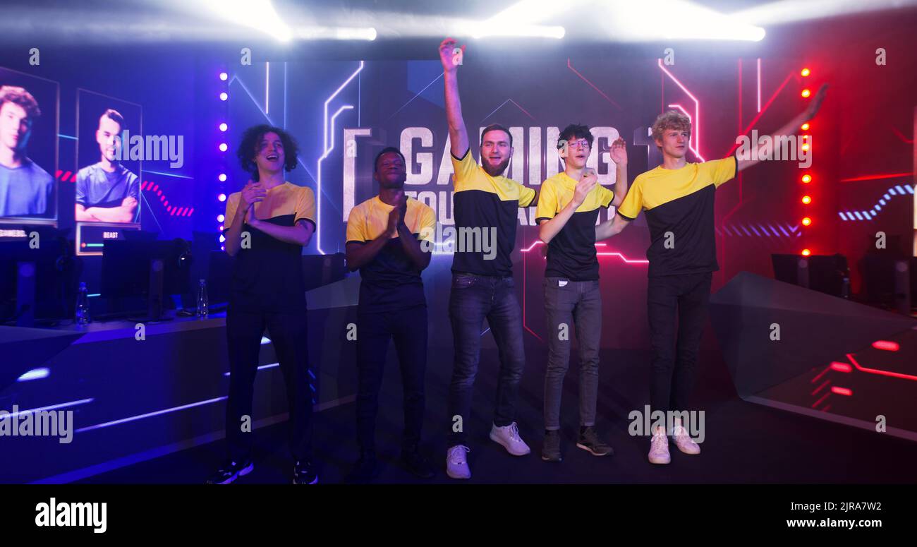 Multiracial young men in yellow team t shirts waving and clapping hands ...