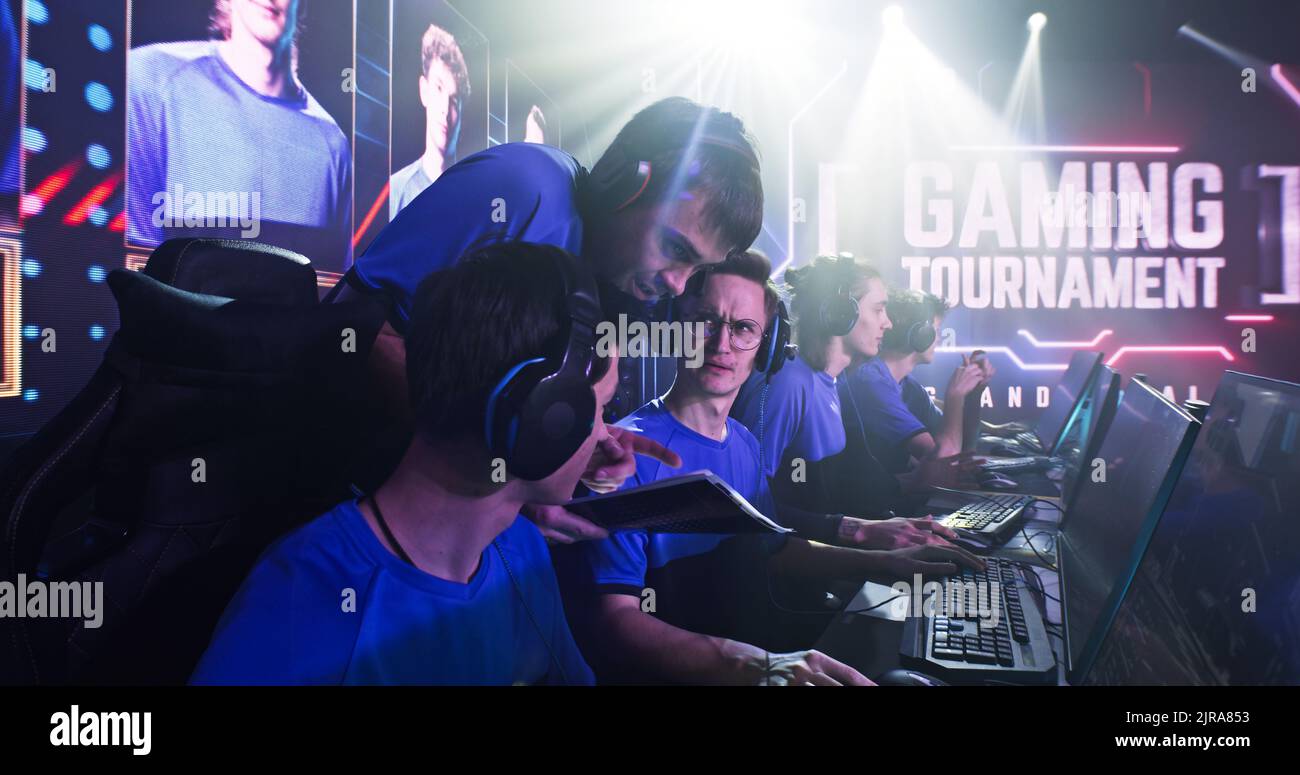 Trainer in headset explaining strategy to young esports gamers at start ...