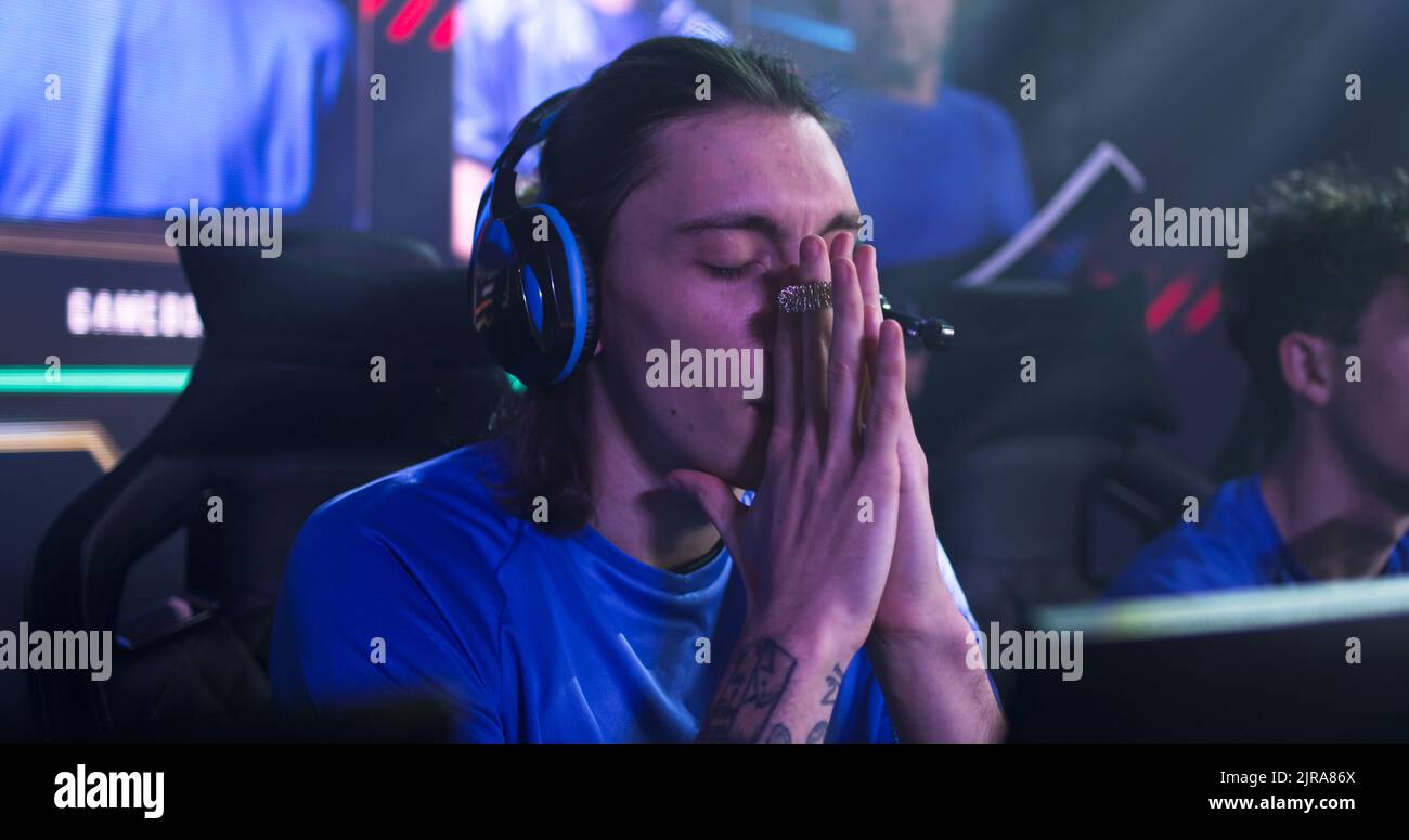 Nervous esportsman gamer rubbing hands and adjusting headphones while ...